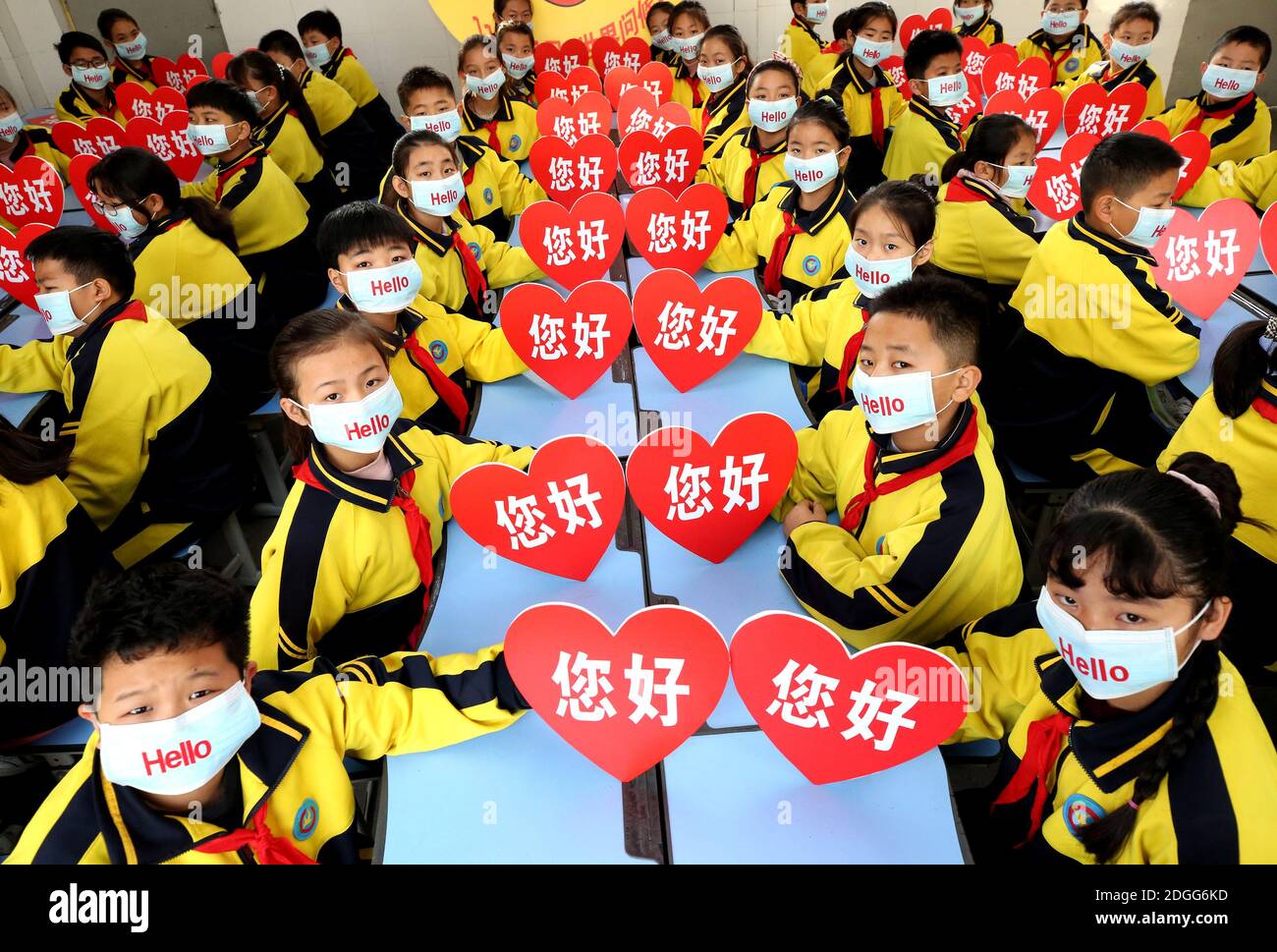 Pupils wear masks with Hello written on them and hold signs in their ...