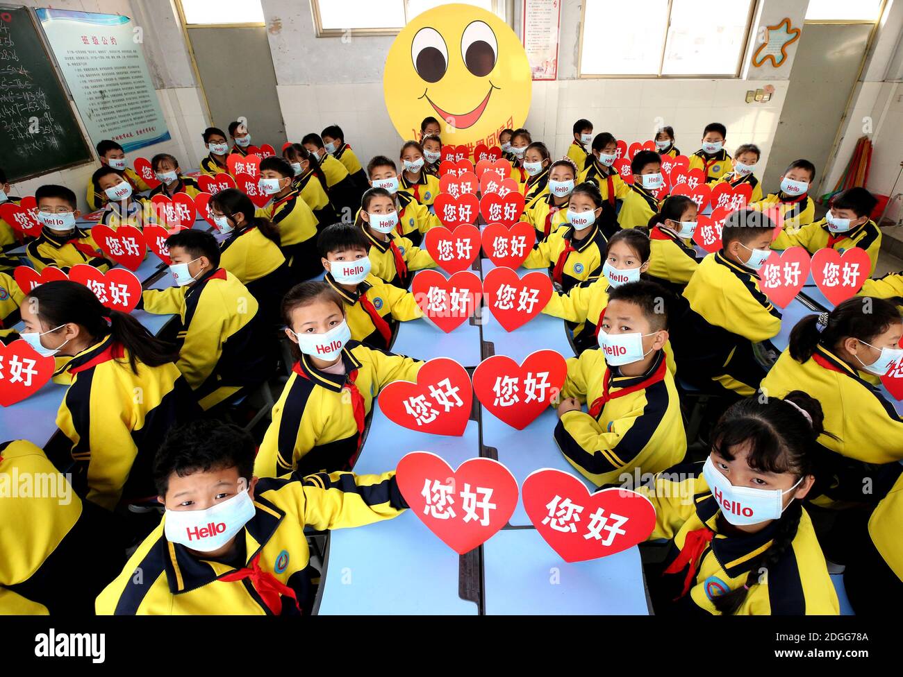 Pupils wear masks with Hello written on them and hold signs in their ...