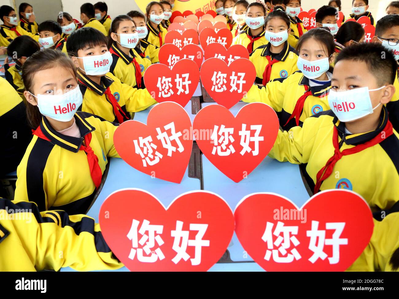 Pupils wear masks with Hello written on them and hold signs in their ...