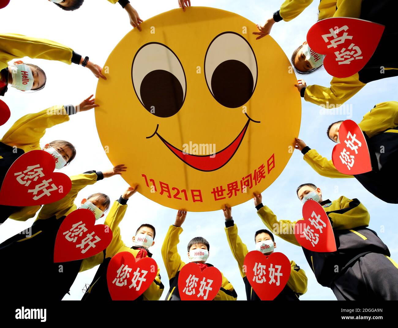 Pupils wear masks with Hello written on them and hold signs in their ...