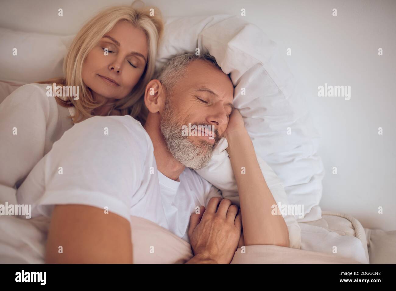 Married couple sleeping on a bed and looking peaceful Stock Photo - Alamy