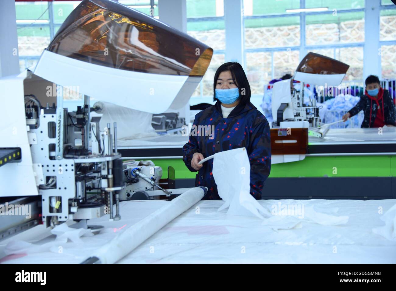 Workers make clothes at an apparel manufacturing company in Enshi city ...