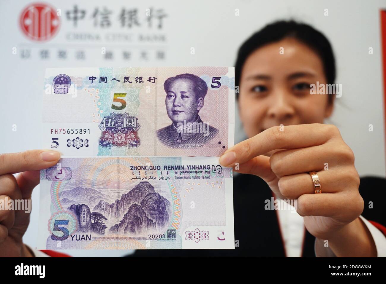 A banker shows the new edition of the 5 yuan banknote of the fifth ...