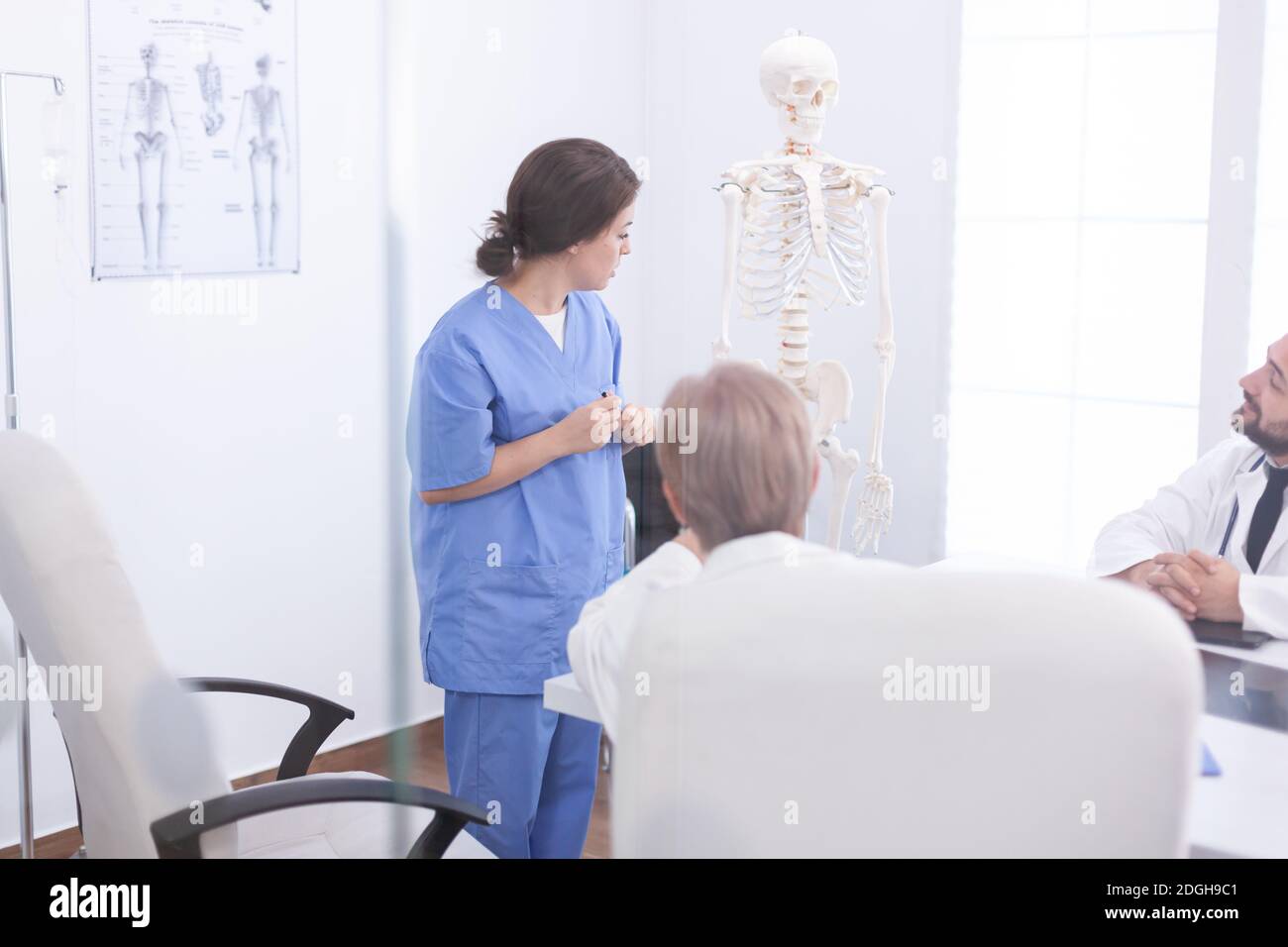 Female nurse doing presentation of human anatomy on skeleton in front ...