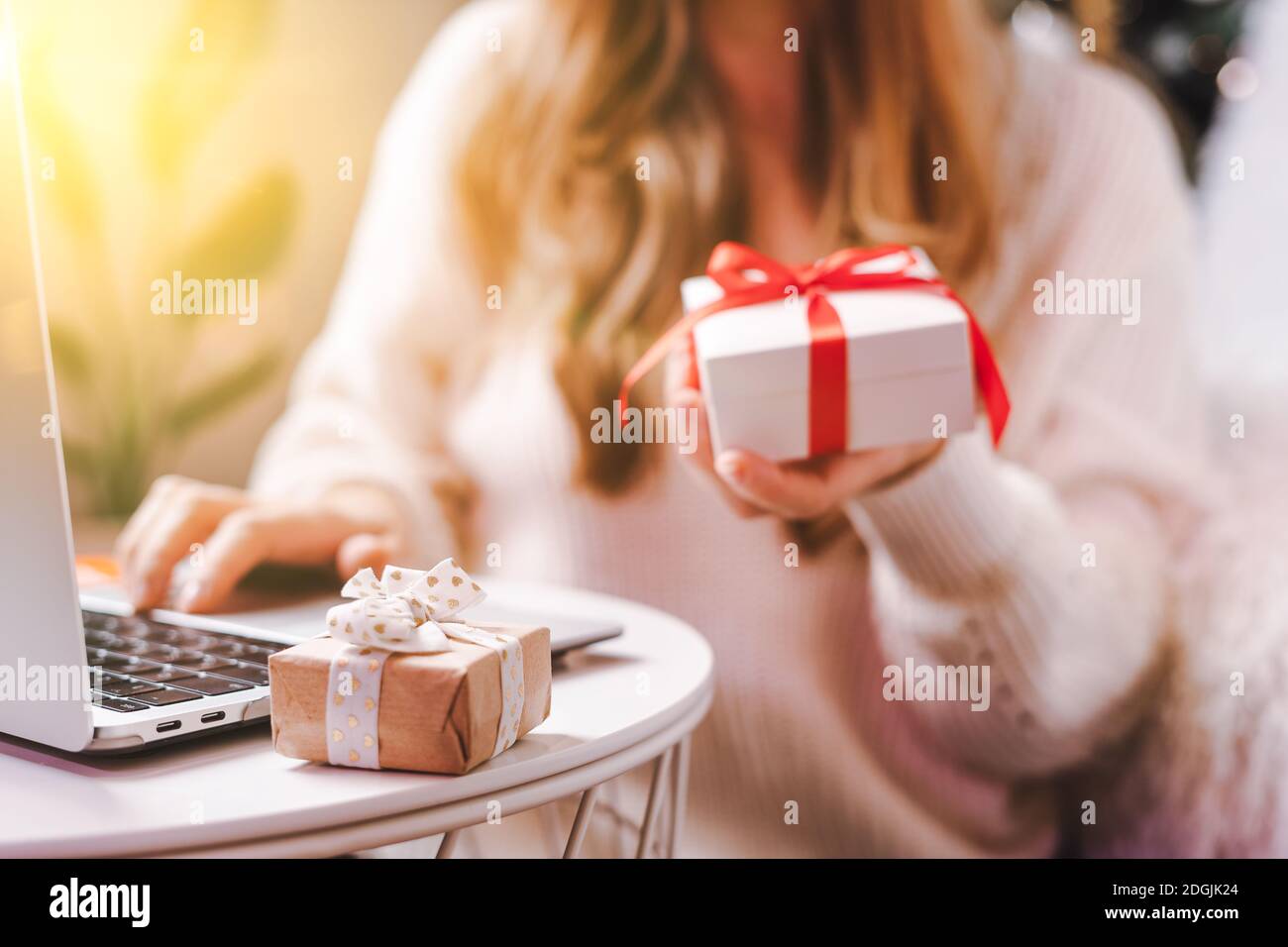 Woman holding gift typing at laptop. Holidays online shopping Stock ...