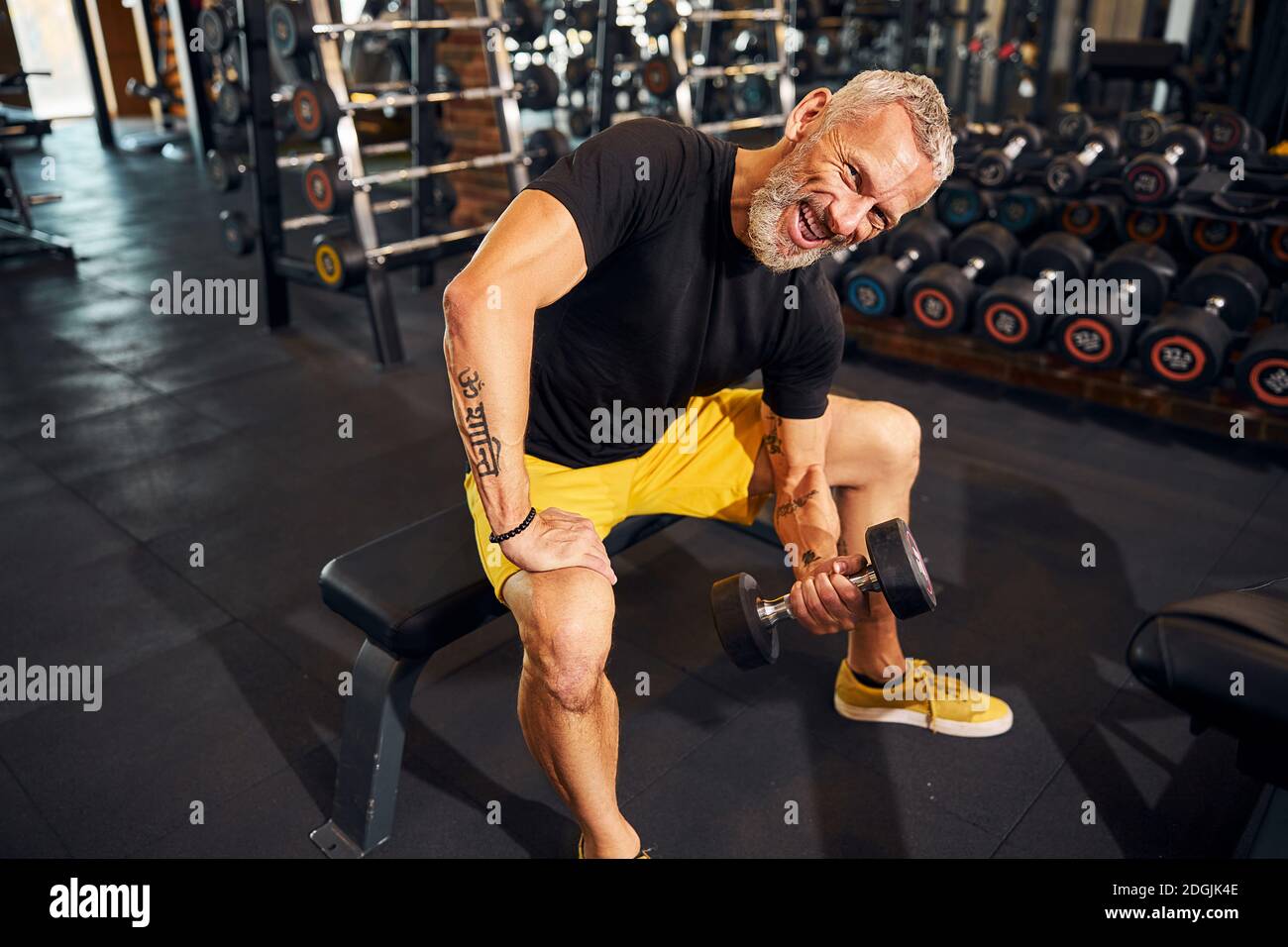 Smiling gray-haired bodybuilder doing the concentration curl Stock ...