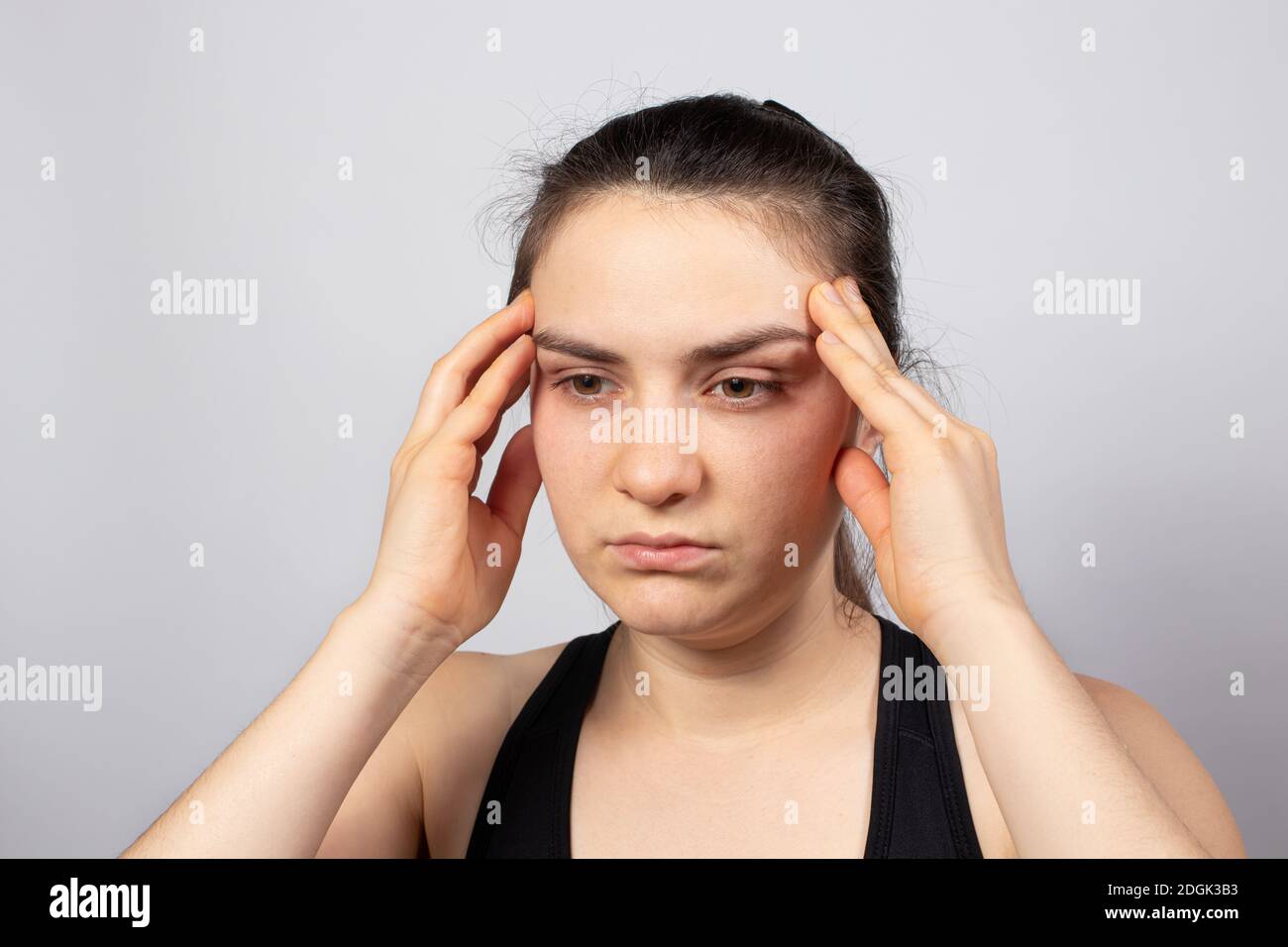 The girl holds her hands by the temple on a light white background ...