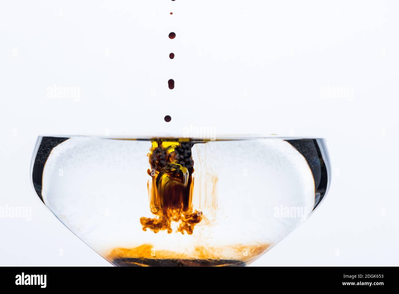 Detail of drops of dark brown balsamico vinegar dripping into glass of ...
