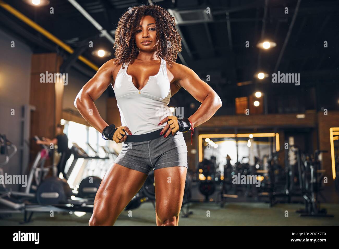 Curly-haired athletic female standing in the fitness center Stock Photo ...