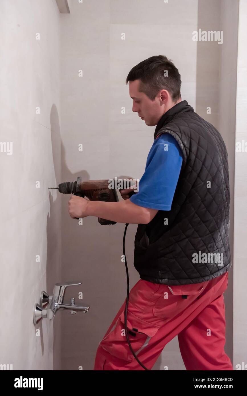 Construction worker drilling holes in the bathroom Stock Photo - Alamy
