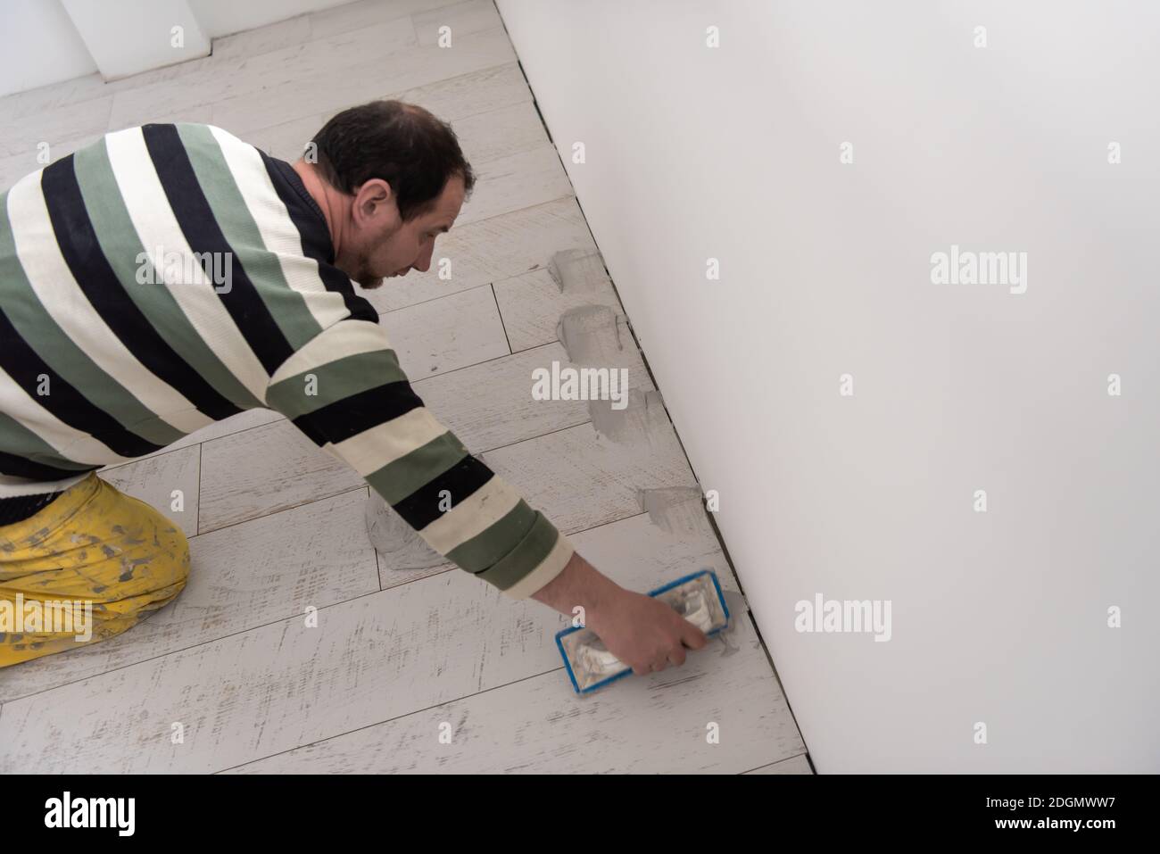Tilers filling the space between ceramic wood effect tiles Stock Photo ...