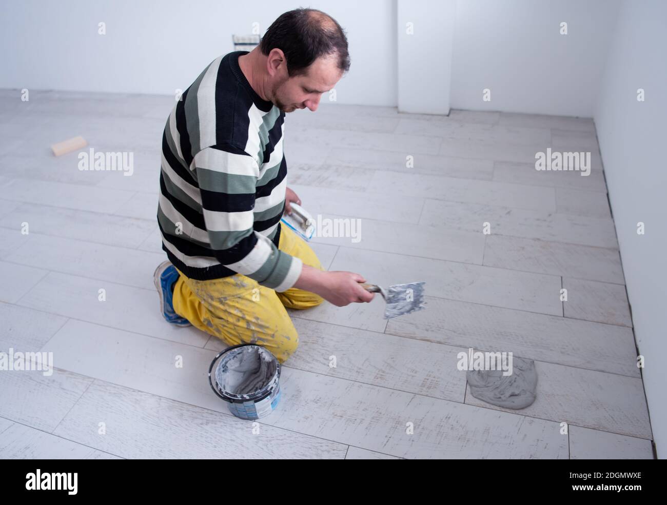 Tilers filling the space between ceramic wood effect tiles Stock Photo ...