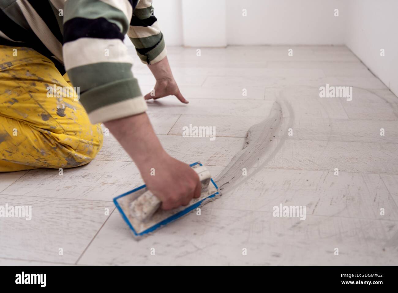 Tilers filling the space between ceramic wood effect tiles Stock Photo ...