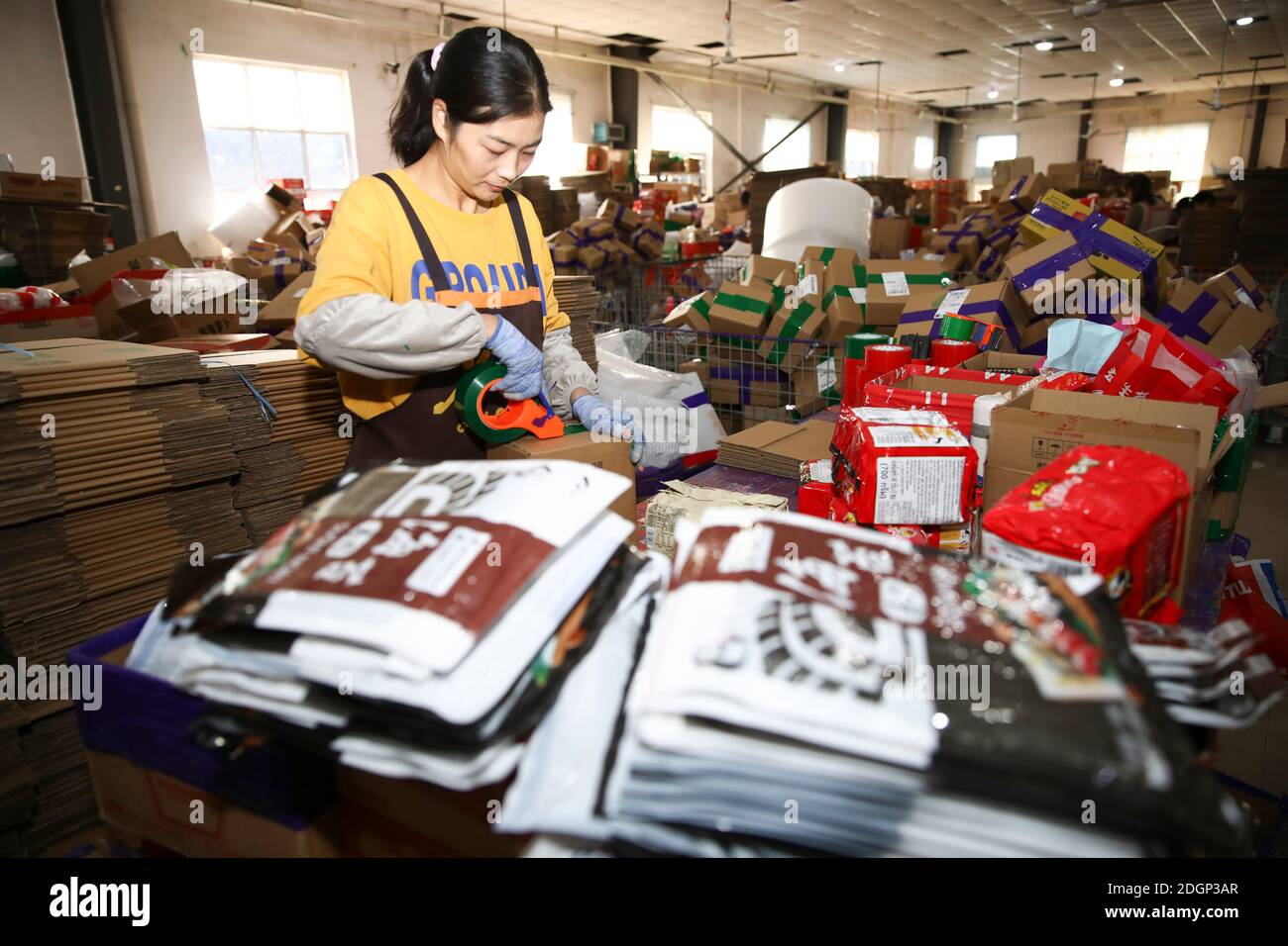 Staff sort and pack goods for deliveries in a logistics center of an e ...