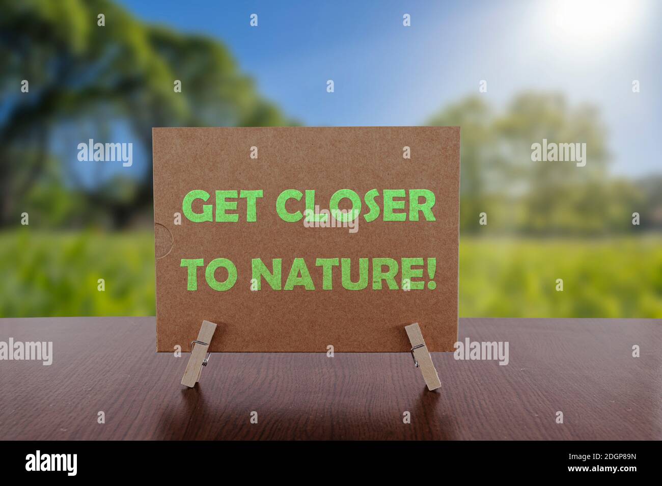 Get closer to nature text on card on the table with sunny green park ...
