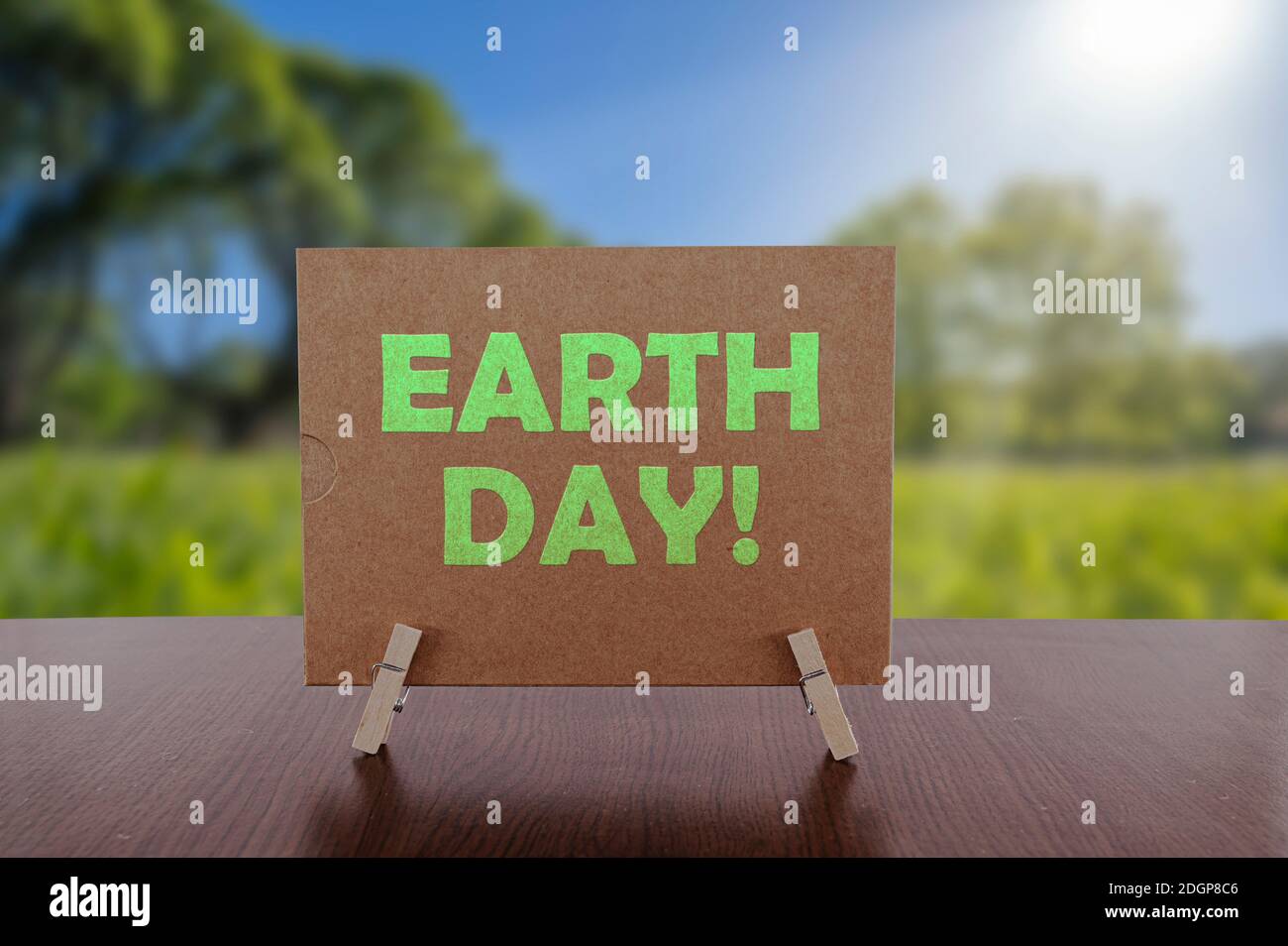 Earth day text on card on the table with sunny green park background ...