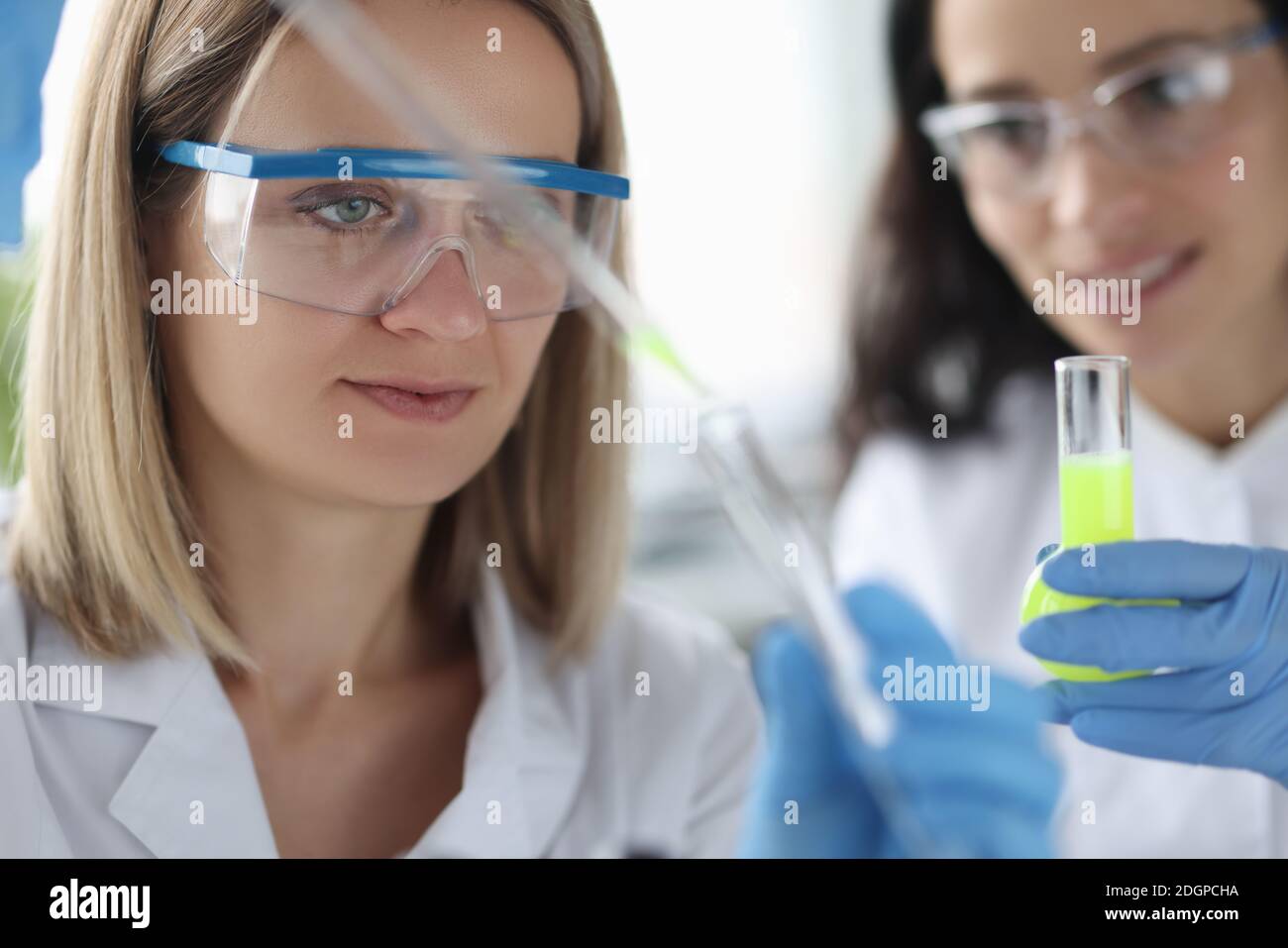 Female scientists pouring chemical liquid from pipette into test tube ...