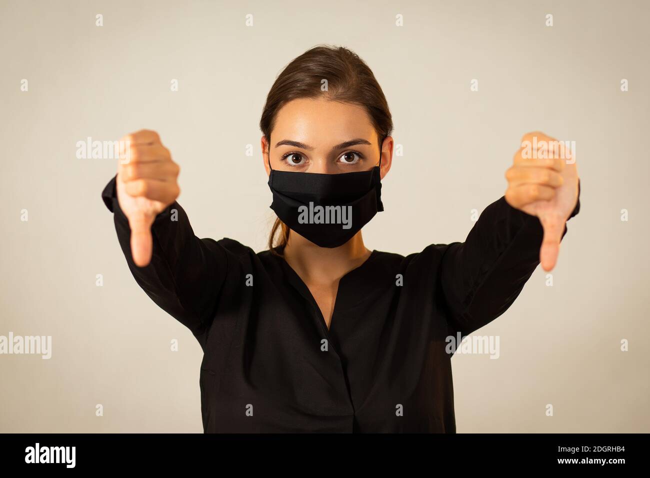 Unhappy young woman wearing black face mask expressing her negative ...