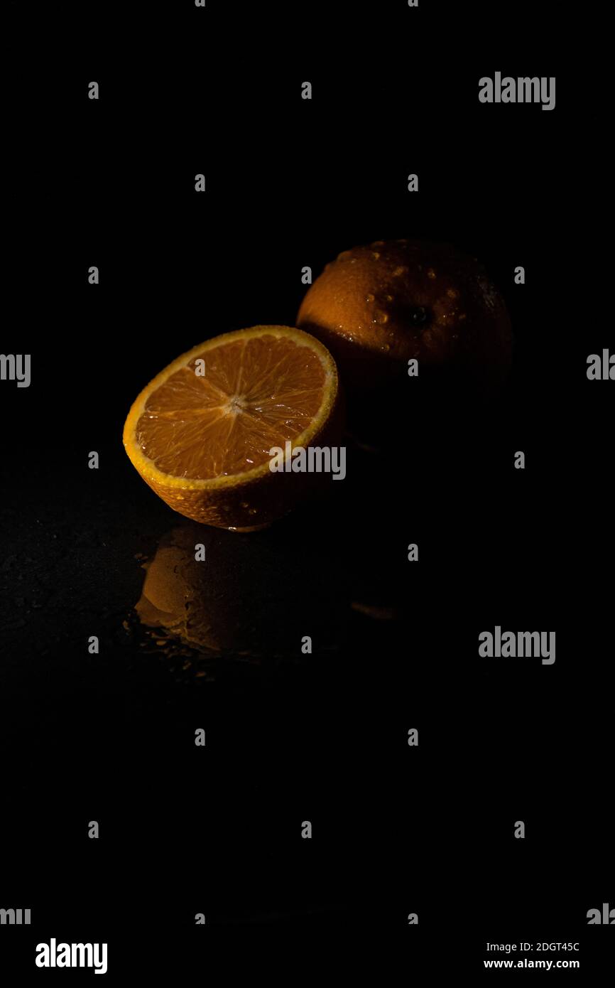 A vertical closeup of sliced oranges isolated on a black background ...