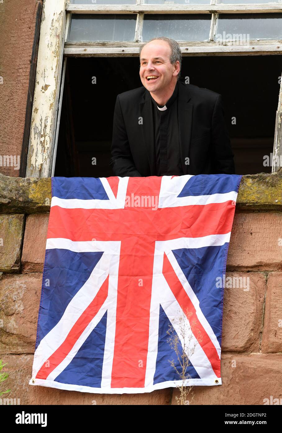 A vicar watches from a window before Queen Elizabeth II and the Duchess ...