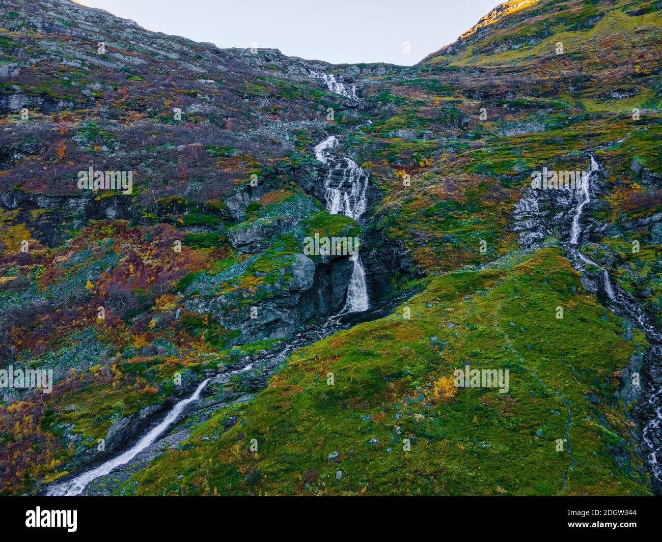 Long narrow waterfall cutting through the terrain on a steep green ...