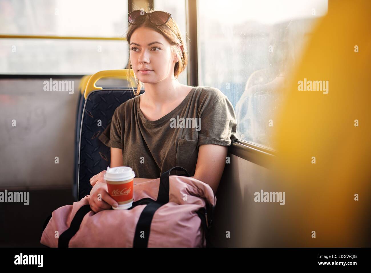 Young adorable woman is sitting on a bus seat holding her bag and ...
