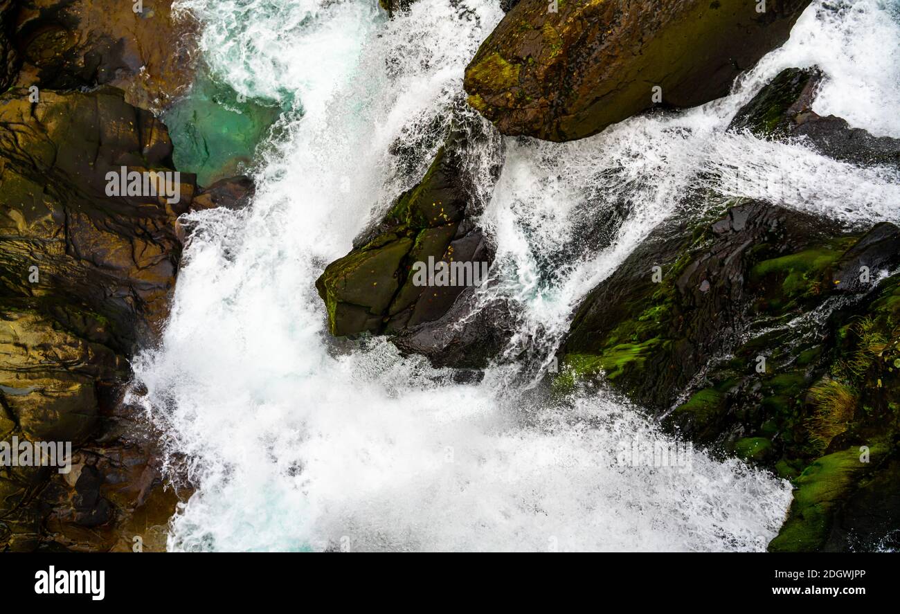 Powerful waterfall cascading down a steep cliff side with lush green ...