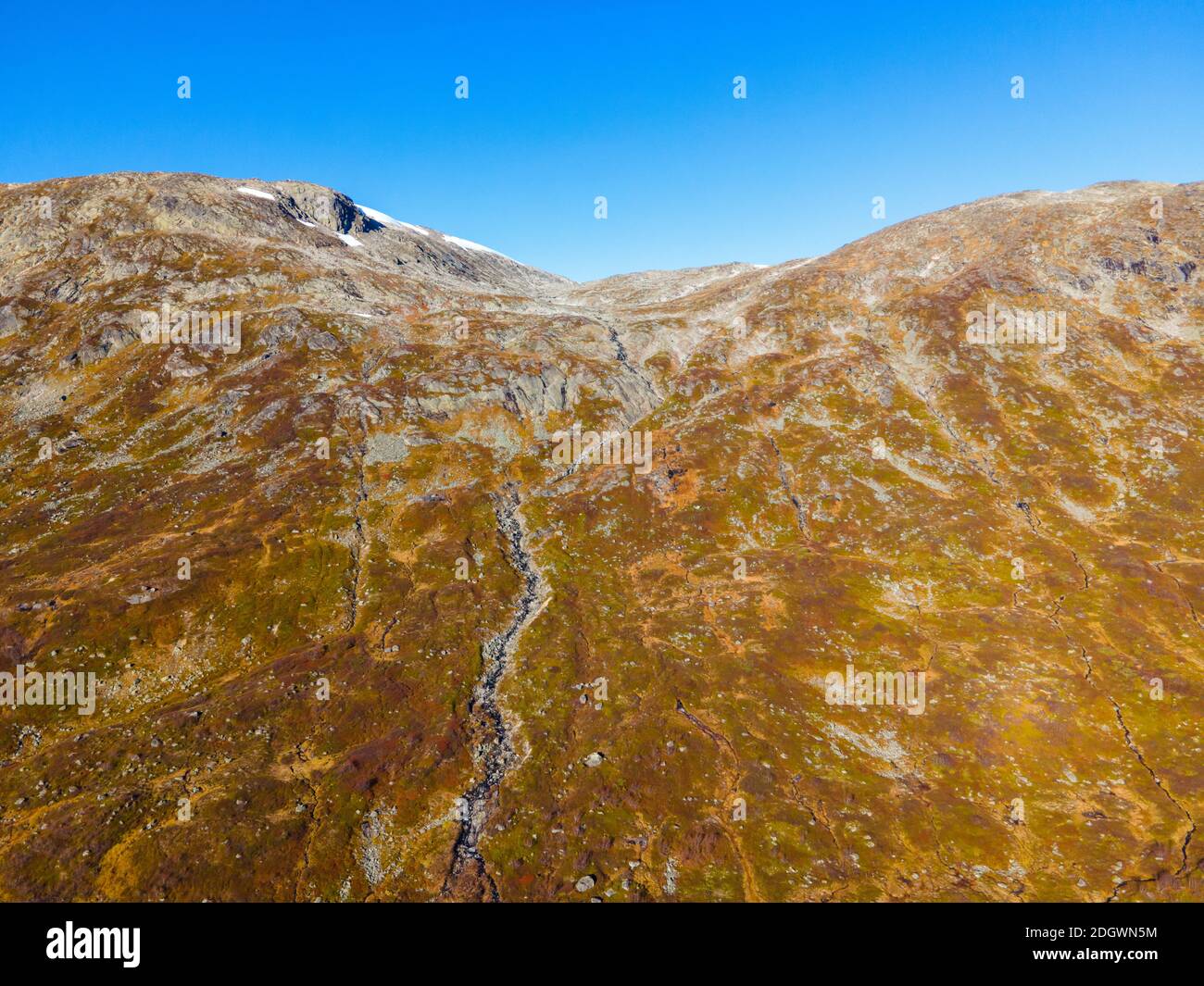 Rugged mountain side in autumn colors with a small waterfall cutting ...