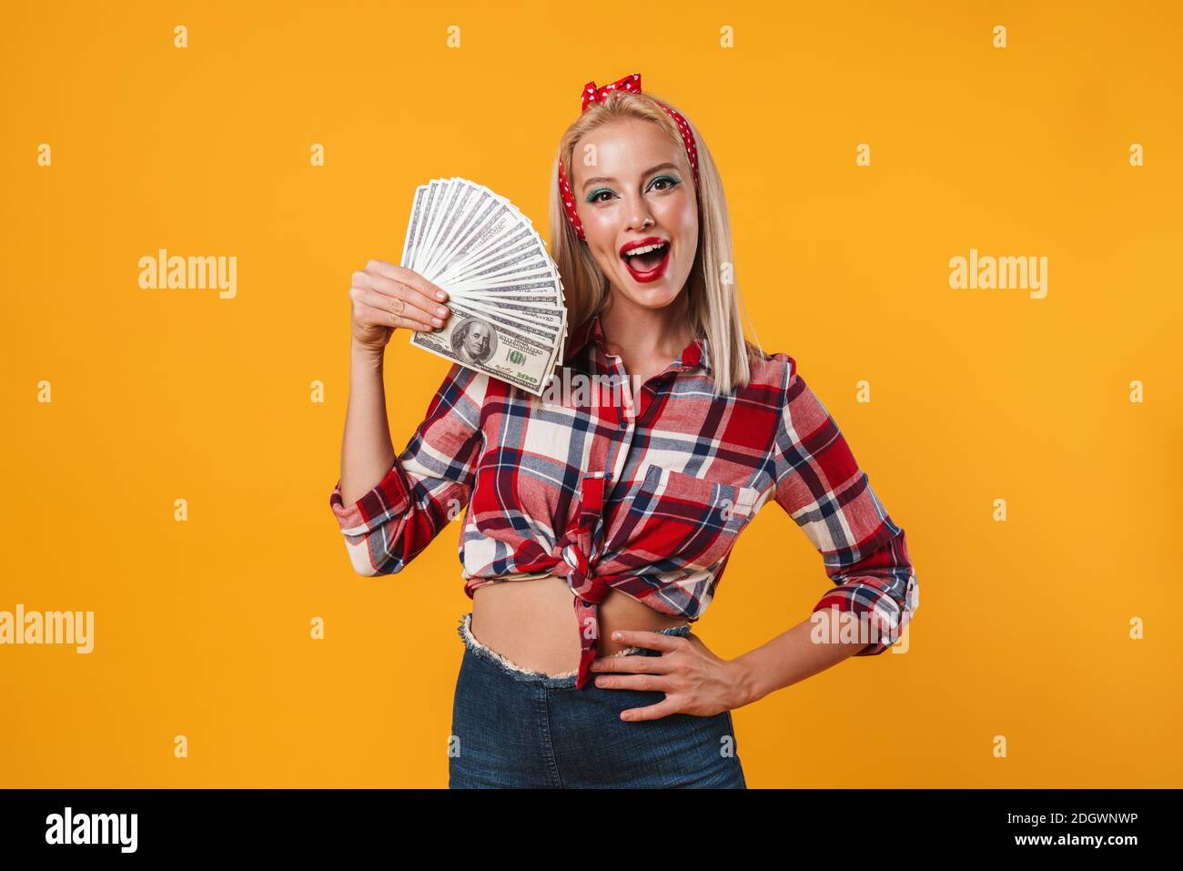 Image of cheerful blonde pinup girl posing with dollars isolated over ...