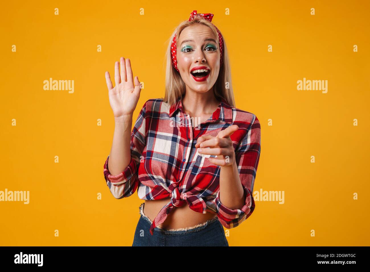 Image of cheerful pinup girl waving hand and pointing finger at camera ...