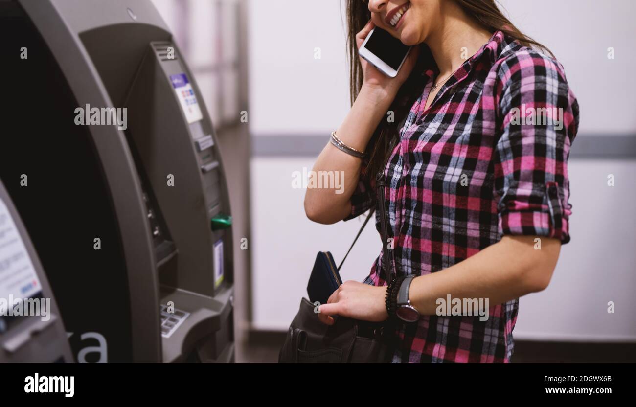 Young cute happy girl is pulling out wallet while taking on the phone ...