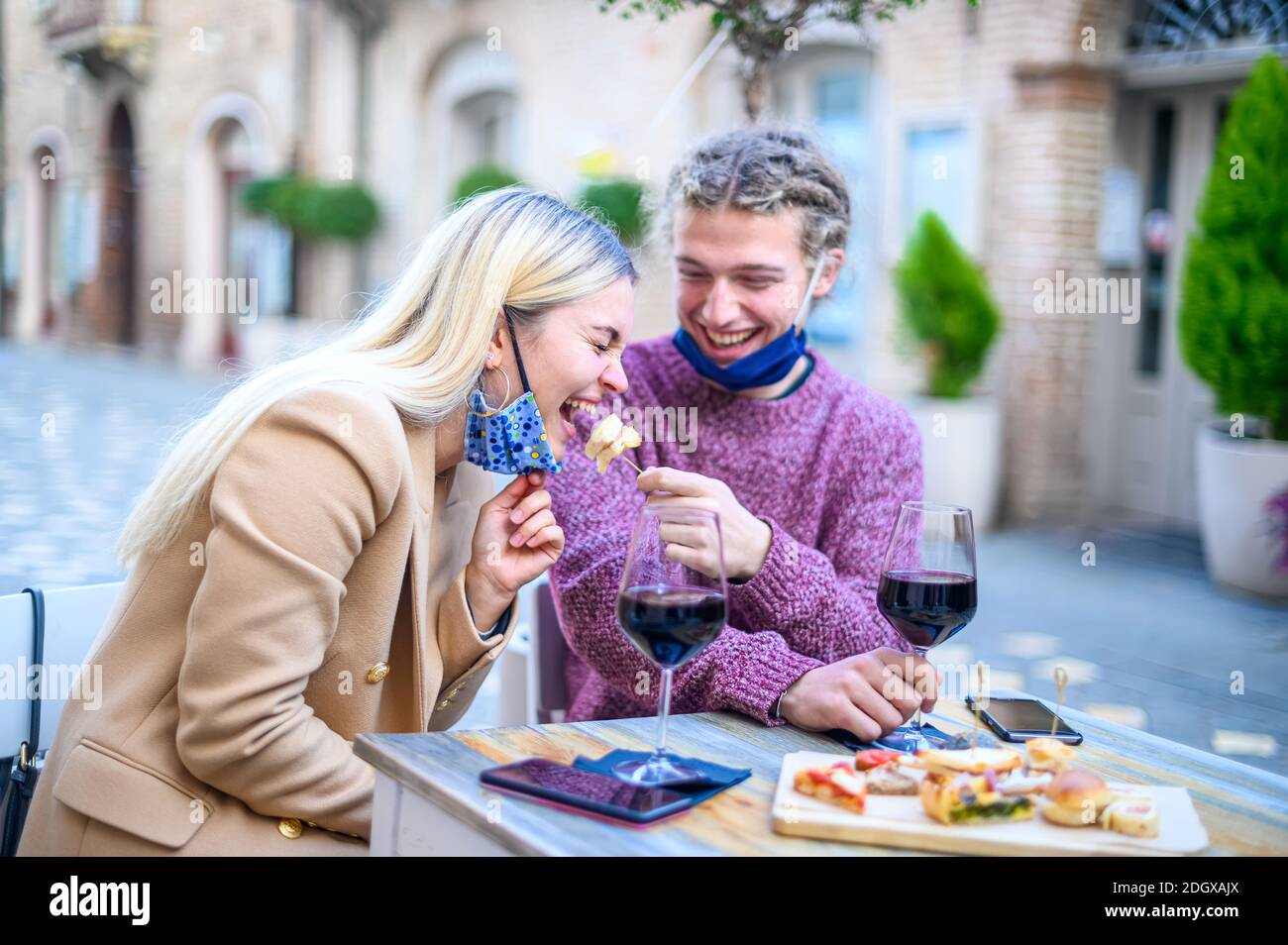 Beautiful happy couple are feeding each other in the restaurant in ...