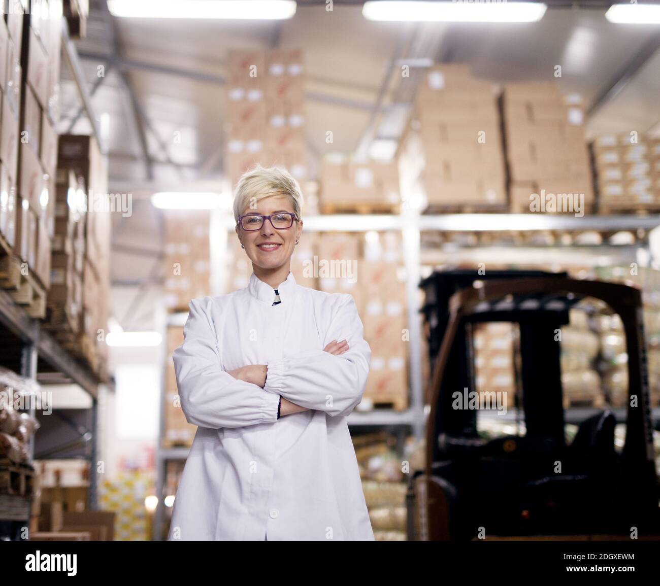 Young beautiful proud female worker is holding her arms crossed and ...