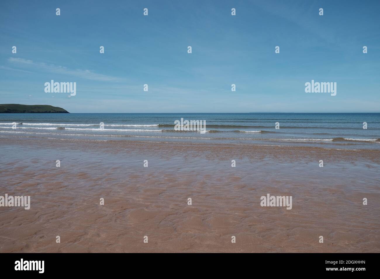 Empty sandy beach looking out to sea with blue horizon, beach is ...