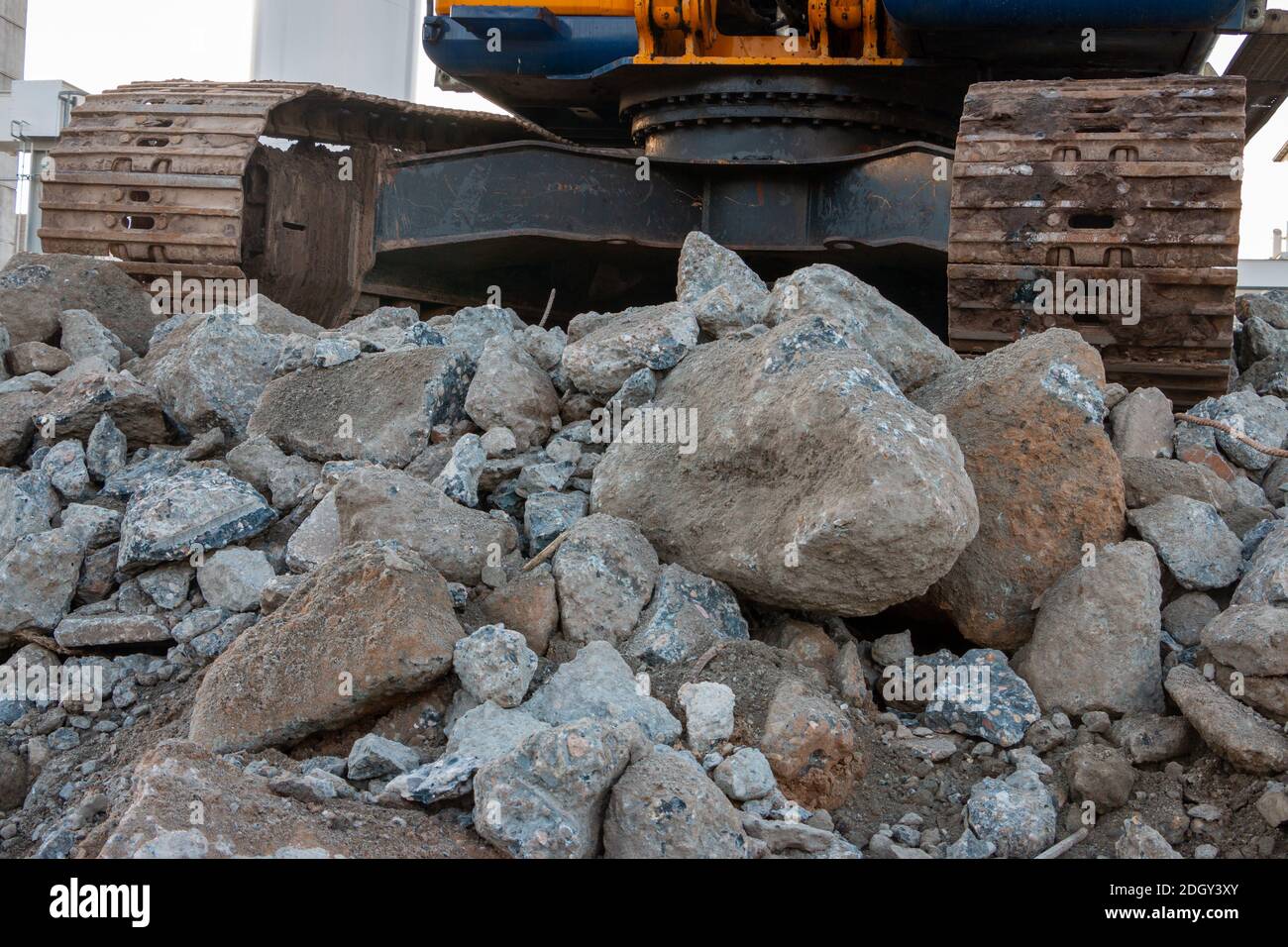 Excavator clearing up concrete waste from a concrete structure in an ...