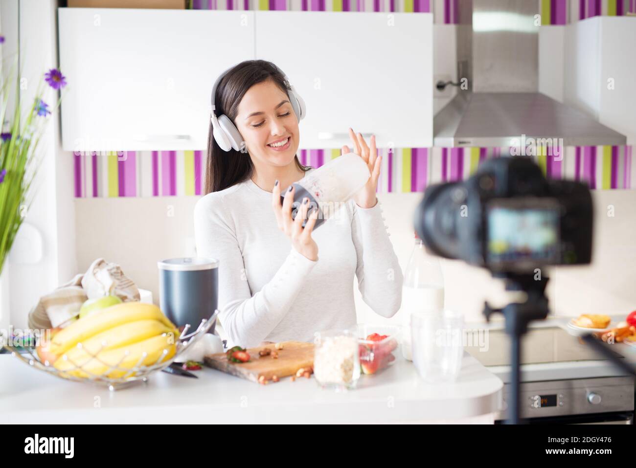 Young beautiful girl shaking smoothie bowl while listening to music on ...