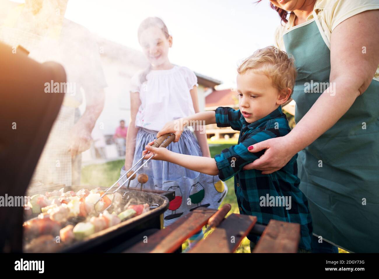 Focused little adorable toddler boy is carefully rotating meat and ...