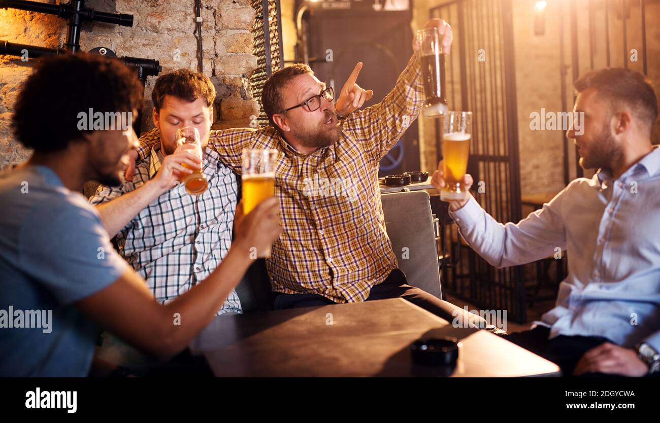 Multicultural cheerful drunk friends sitting hugged in the bar and ...