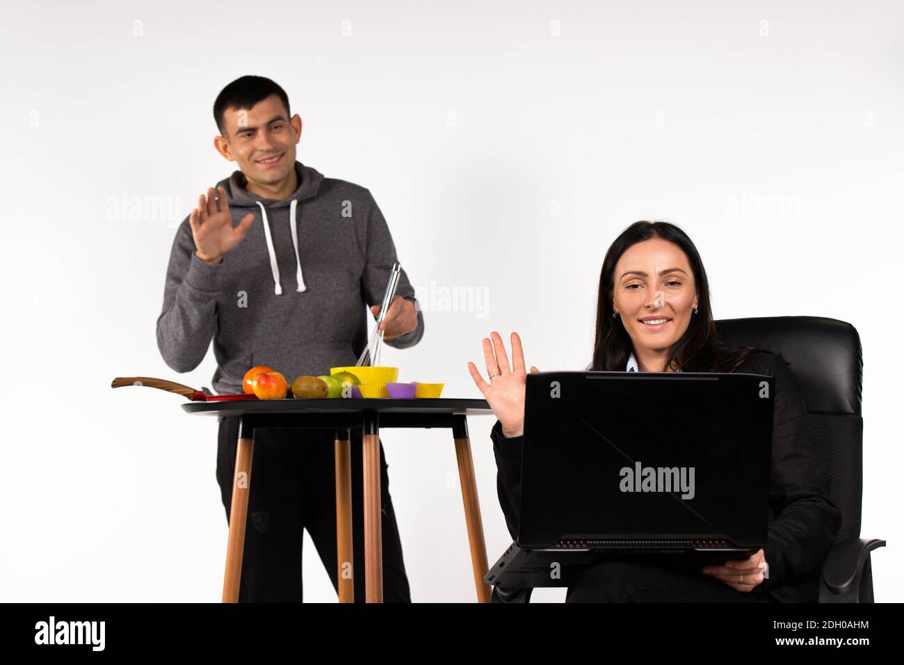 A man is cooking in a kitchen near a woman communicating via video call ...