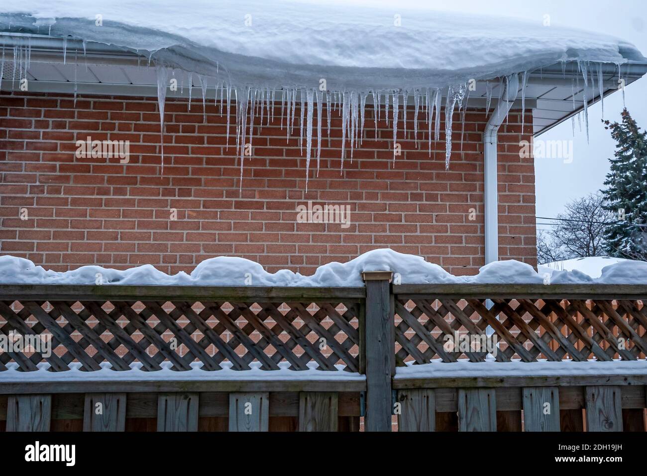 Winter scene - House roof covered with fresh snow with ice pikes ...