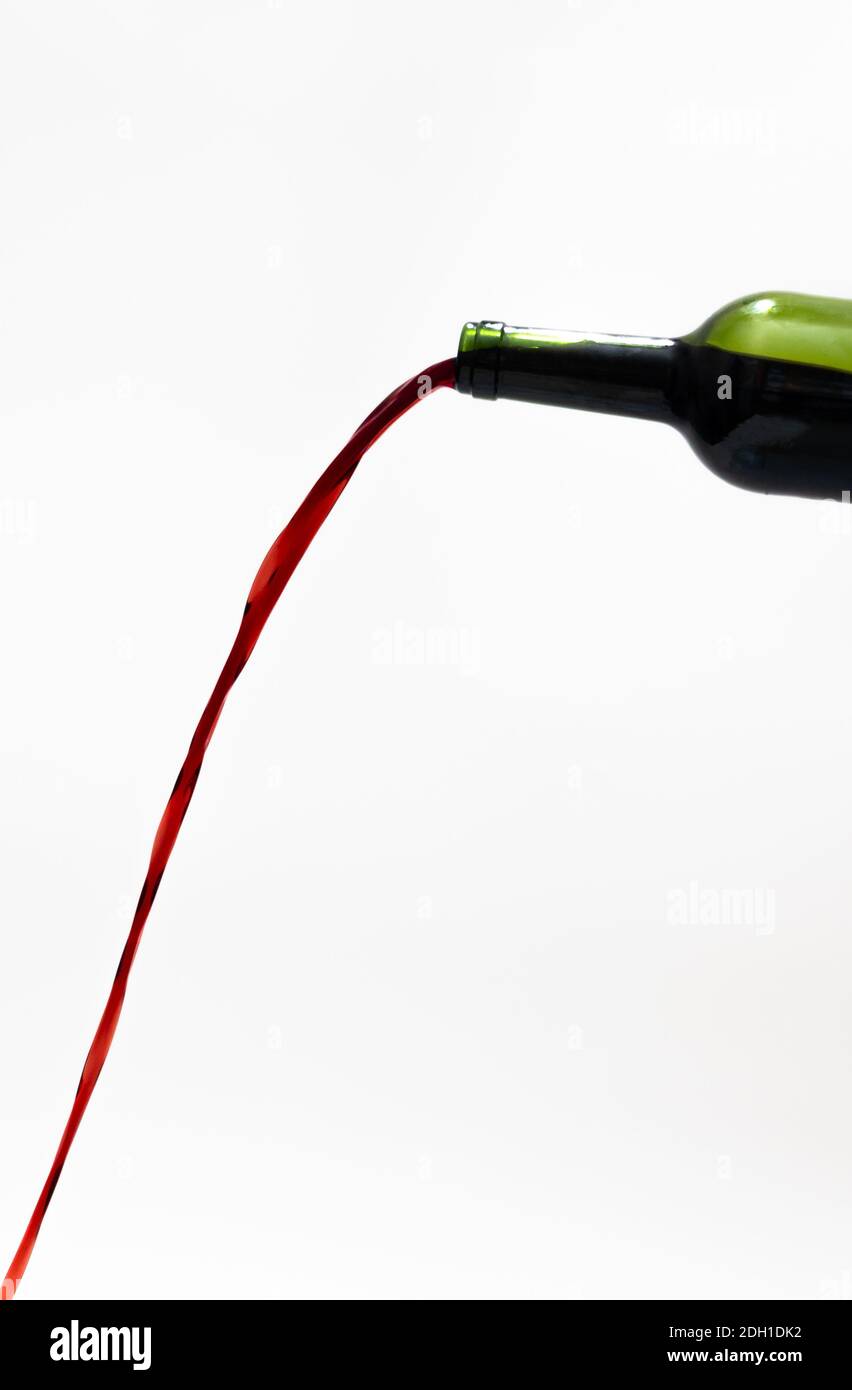 Isolated red wine pouring out of a bottle with long stream on white ...