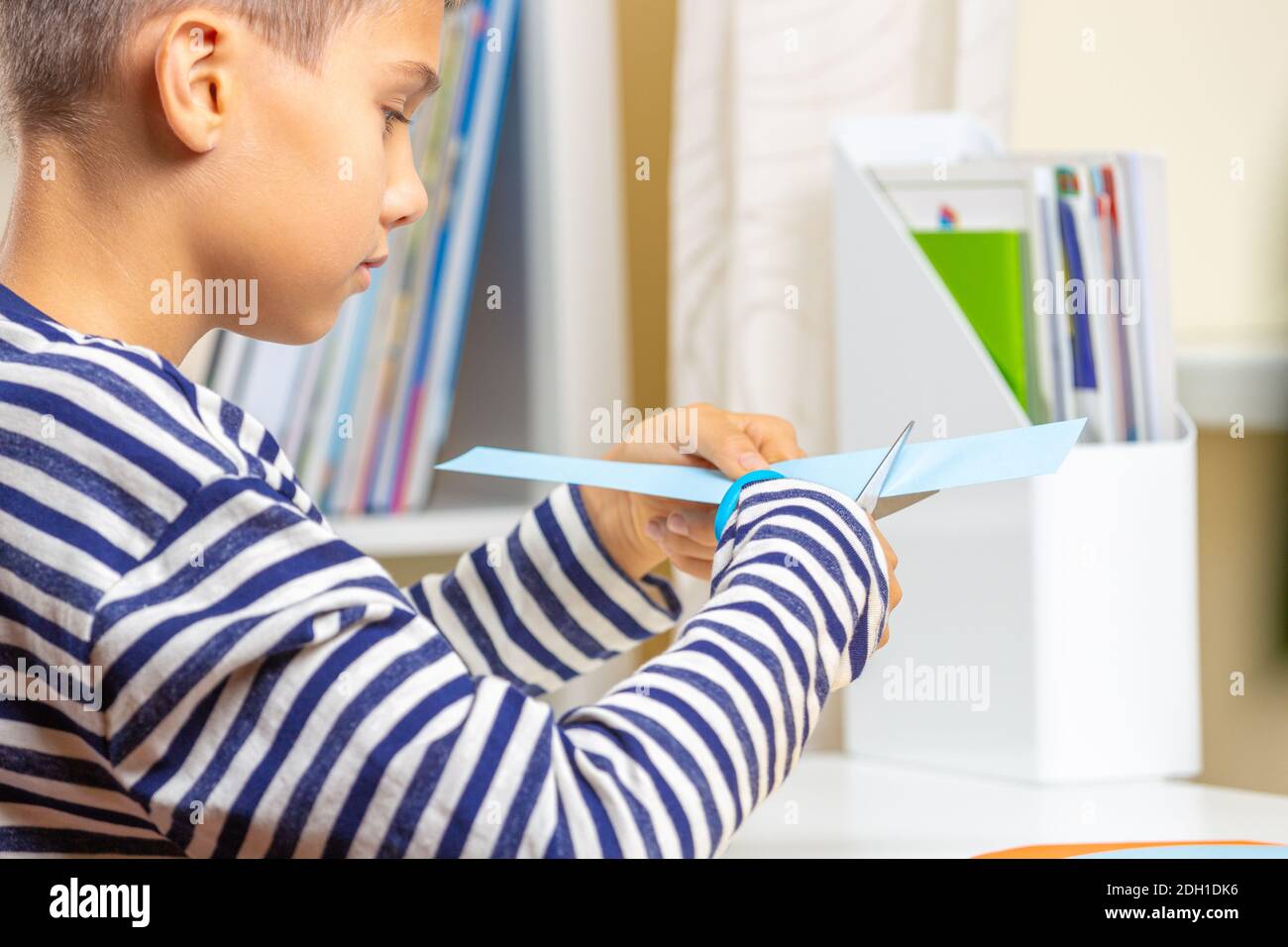Education, learning, paper craft, entertainment. Boy cutting colored ...