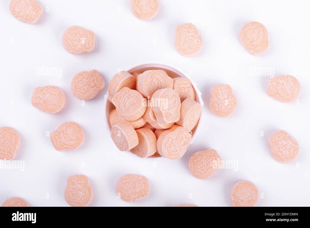 A top view of animal drawings on pink ecstasy pills in a lid isolated ...