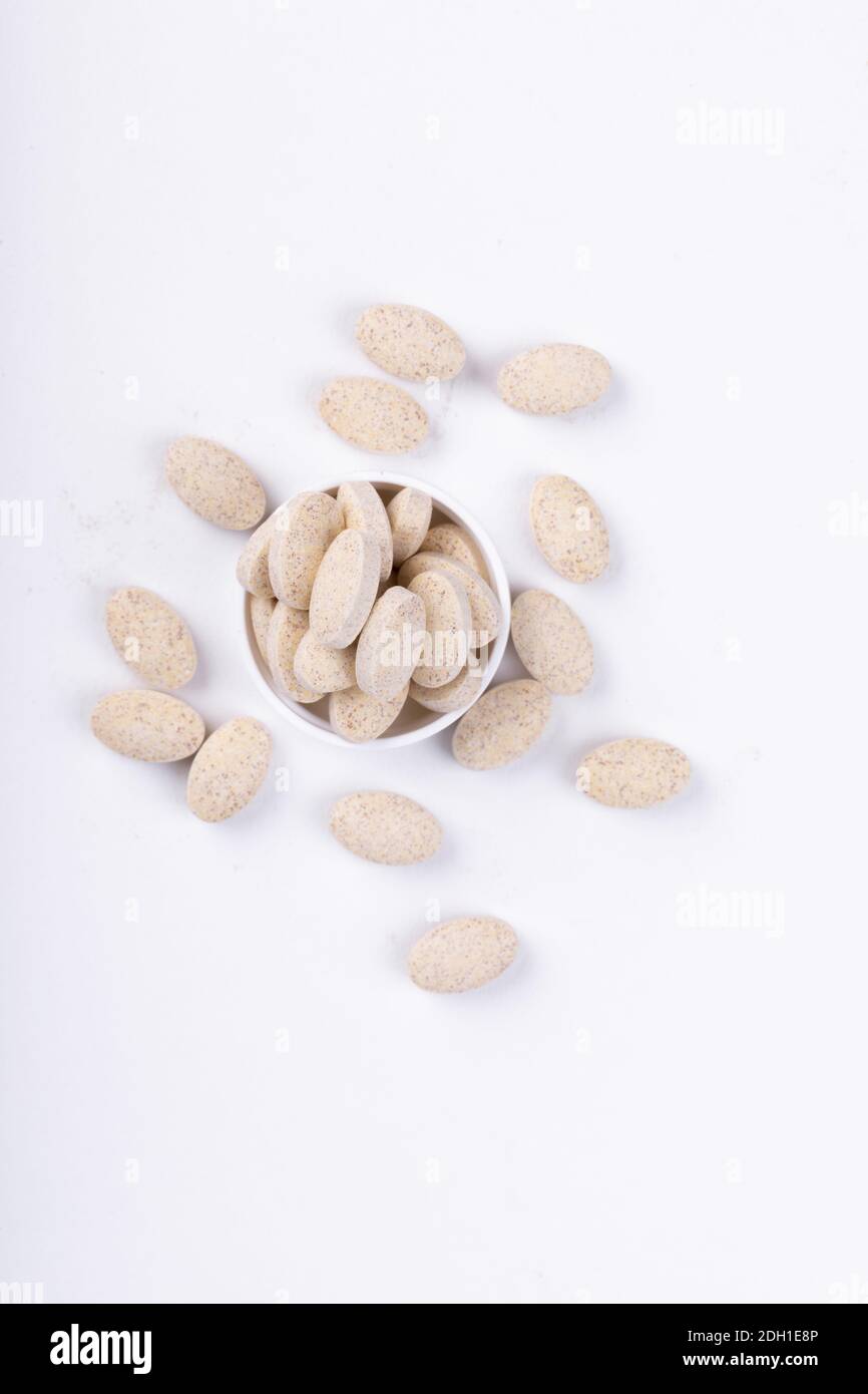 A top view of light brown tablets on white lid isolated on white ...