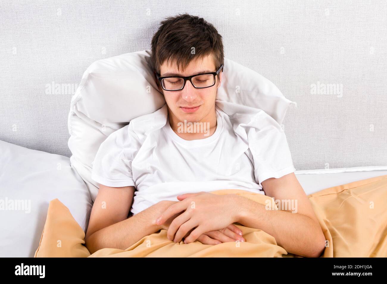Tired and Sleepy Young Man in the Bed by the Wall Stock Photo - Alamy