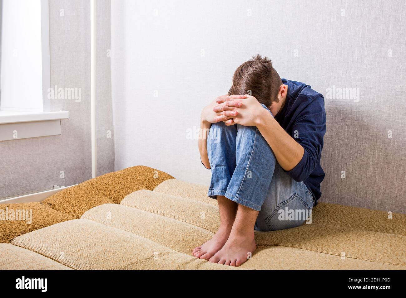 Sad Young Man on the Couch in the Room Stock Photo - Alamy