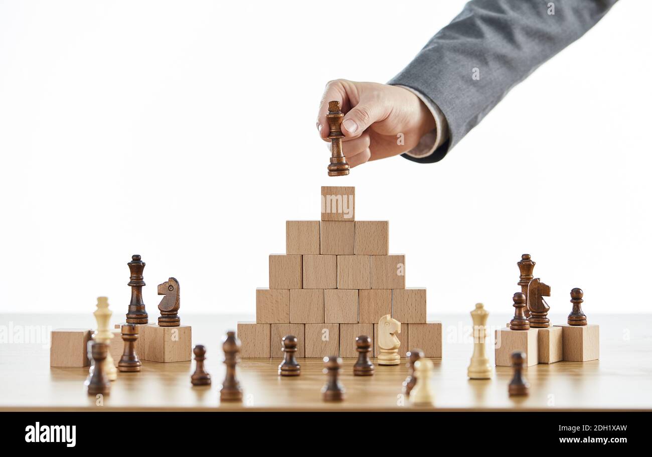A businessman in a suit arranging chess pieces on wooden blocks on ...