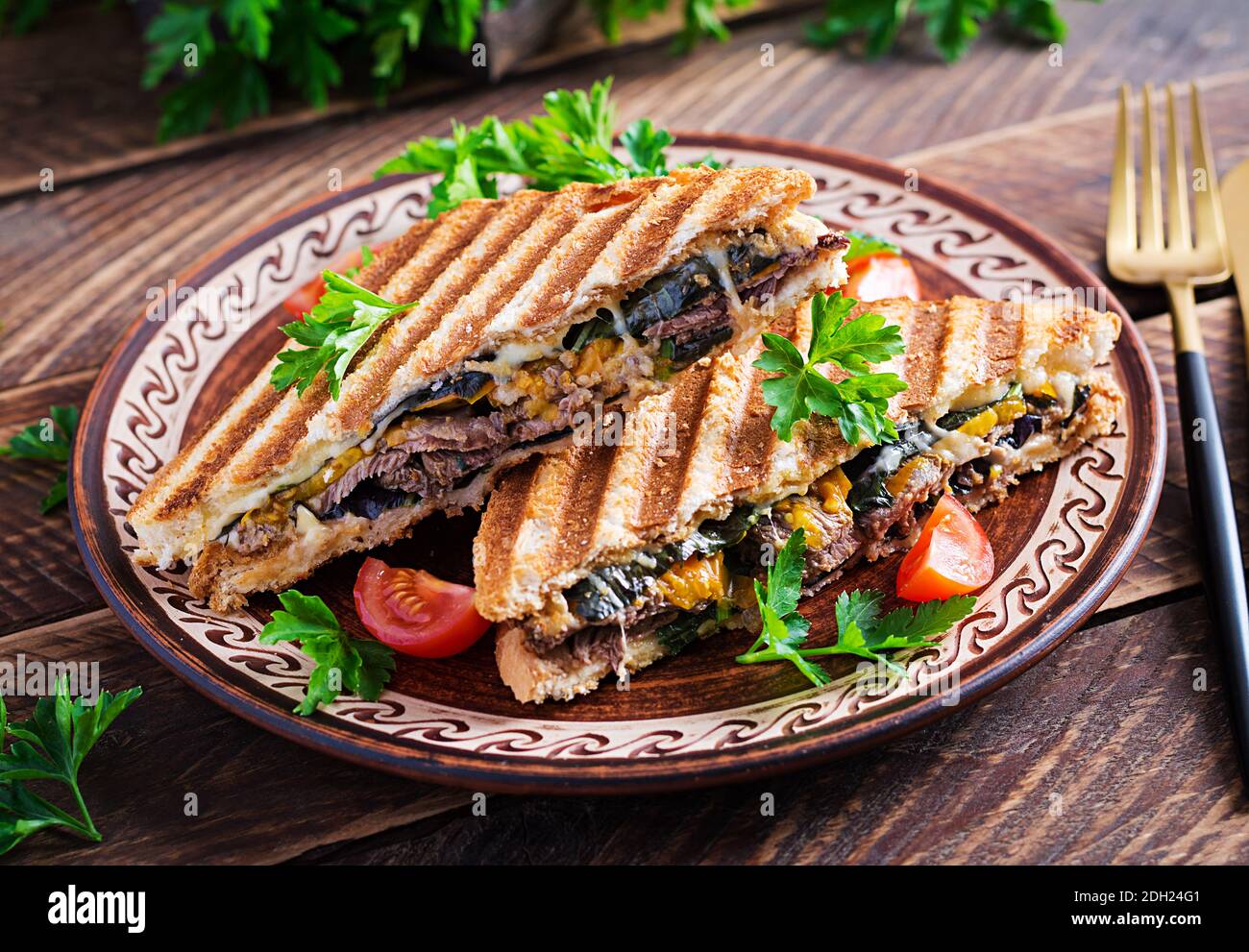 Grilled club sandwich panini with beaf, tomato, cheese and leaf mustard ...