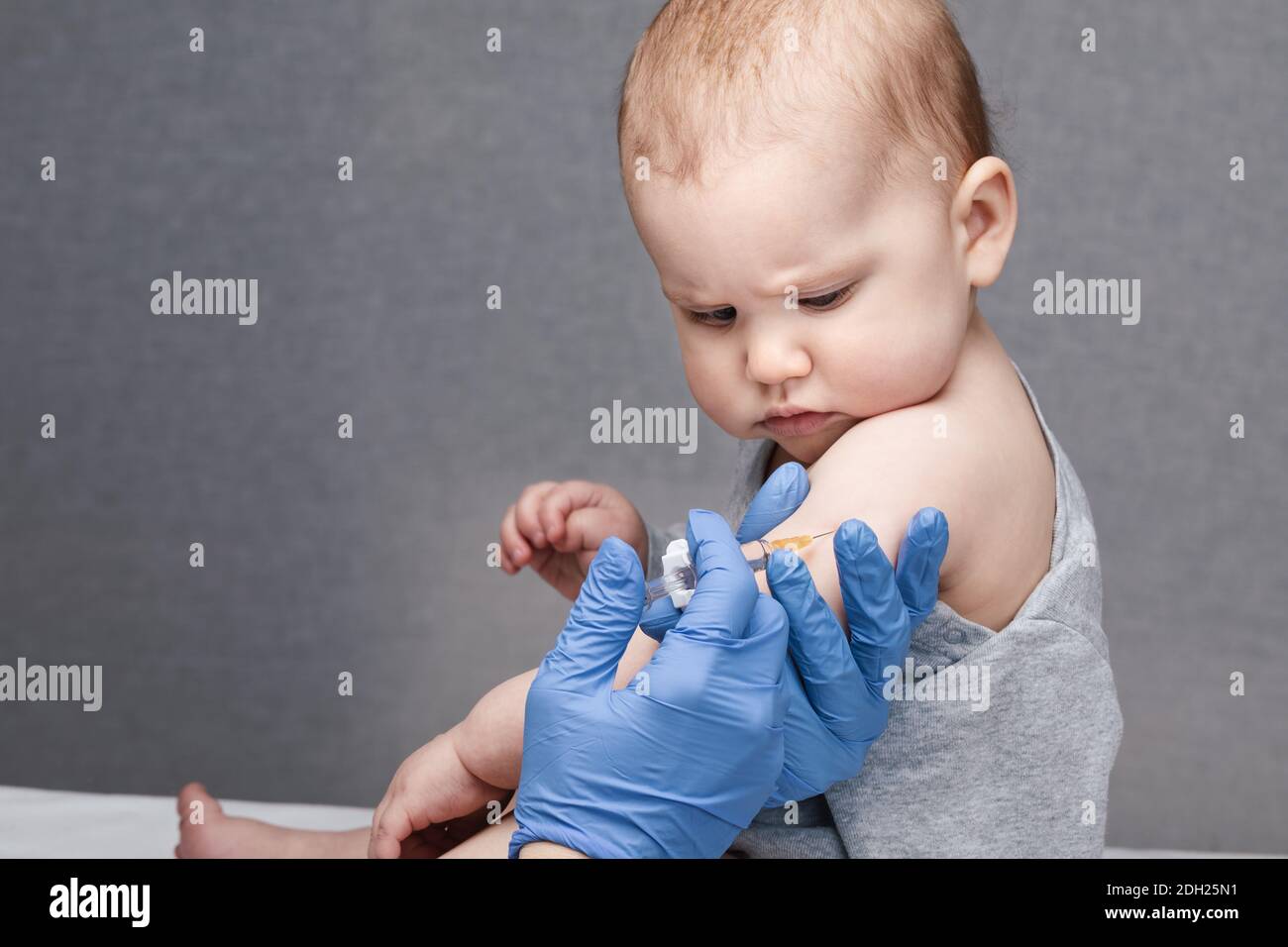 Pediatrician or nurse giving an intramuscular injection of a vaccine to ...
