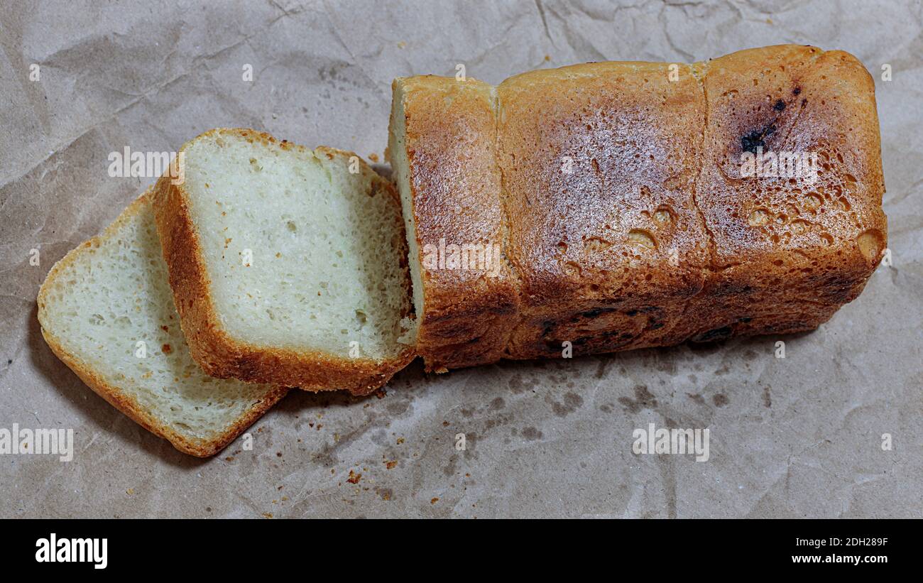 a close-up photo of freshly baked partially sliced bread on a sheet of ...